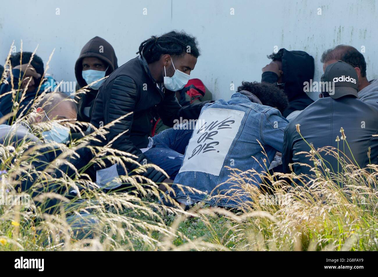 A group of people thought to be migrants sit in the shade after being ...