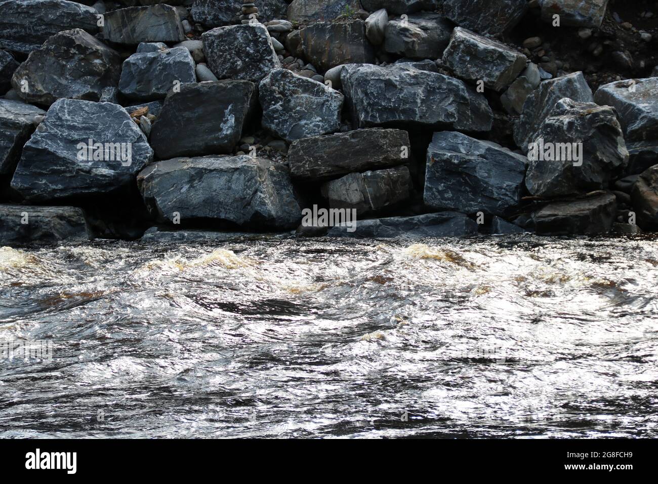 Fast river with boulder strewn river bank Stock Photo - Alamy