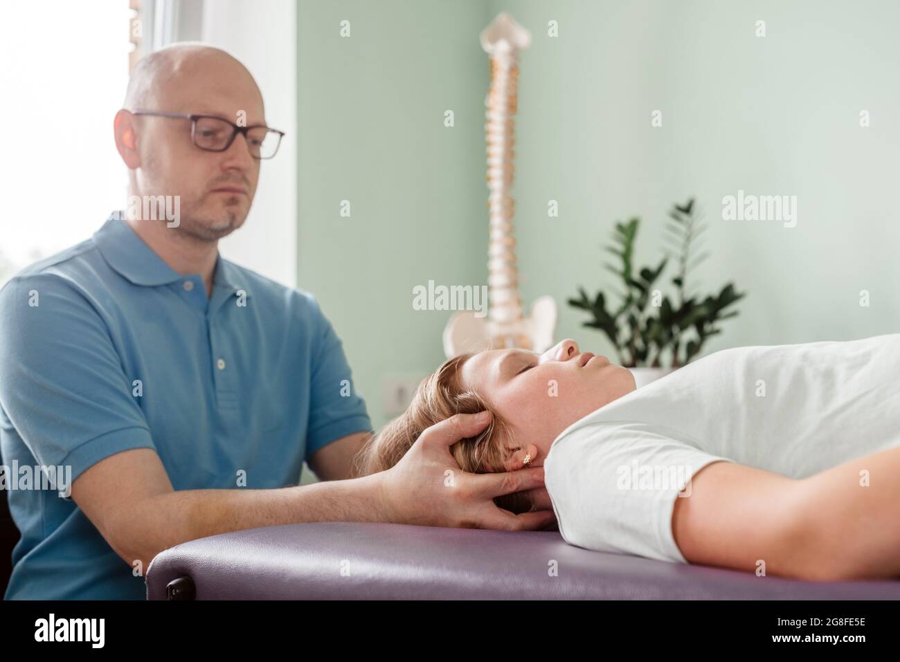 Craniosacral therapy practitioner giving a girl patient CST osteopathic ...