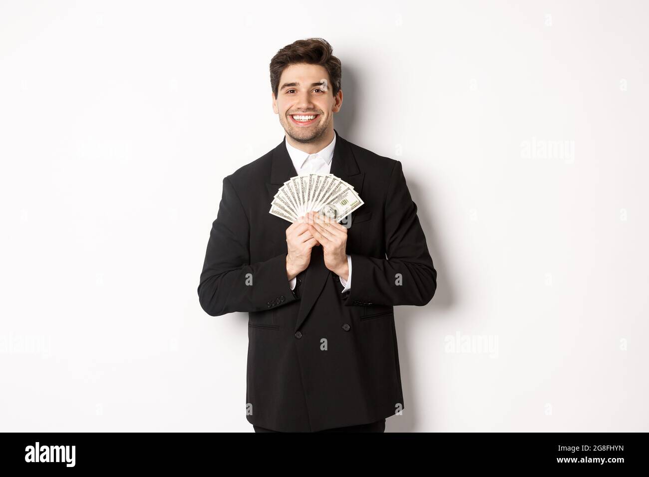 Portrait of happy and pleased handsome man in suit, hugging money and ...