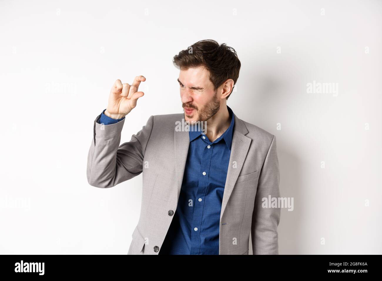 Businessman trying to see something tiny, showing little thing size ...