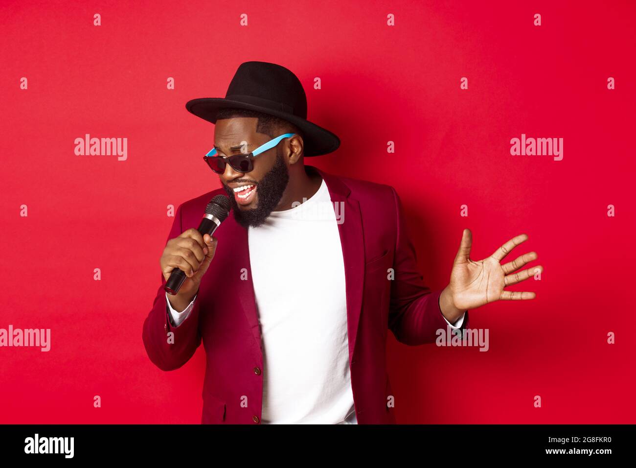 Passionate black male singer performing against red background, singing ...