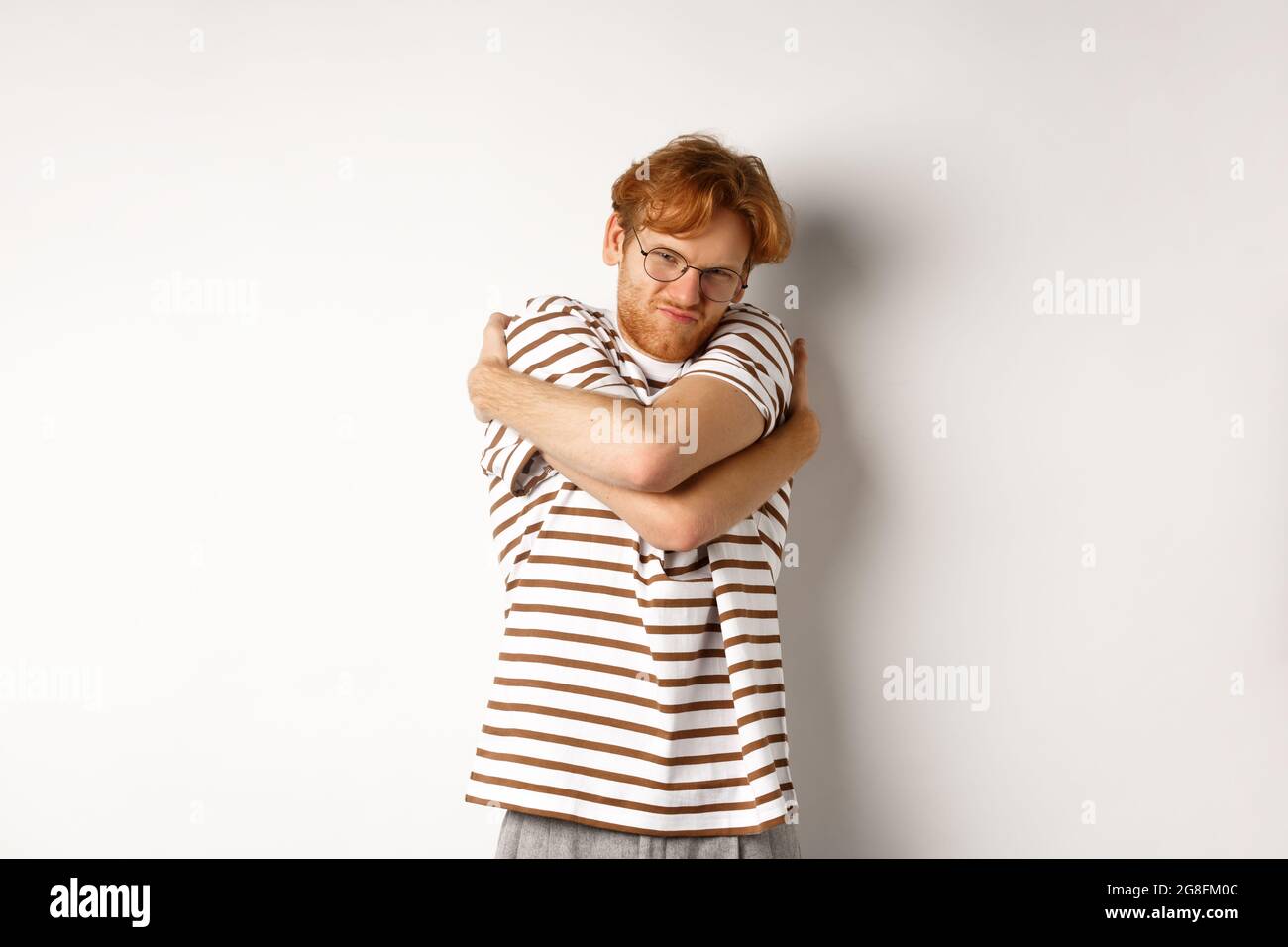 Reluctant young man with messy red hair unwilling do something, hugging ...