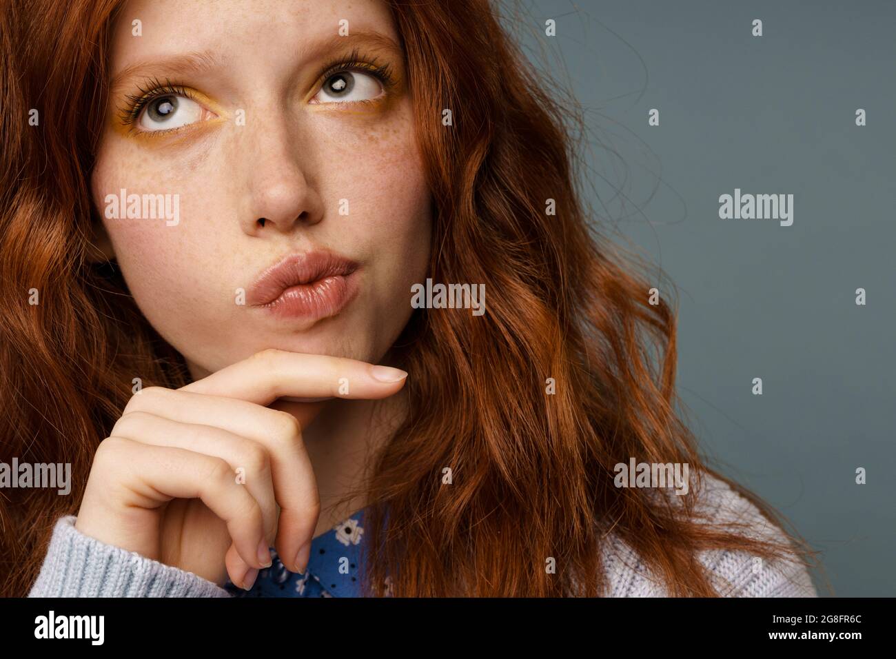 Young ginger puzzled woman thinking and looking upward isolated over ...