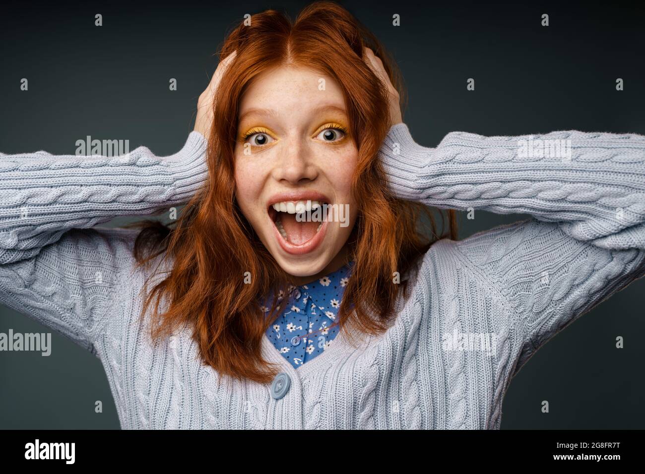 Young ginger excited woman screaming while holding her head isolated over grey background Stock ...