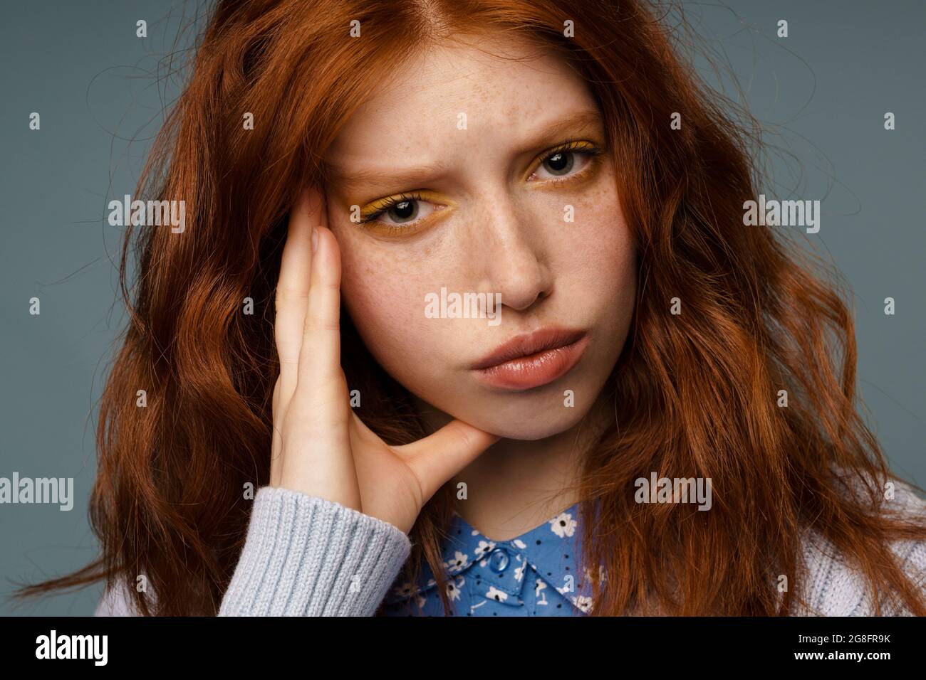 Young ginger puzzled woman thinking and looking at camera isolated over ...