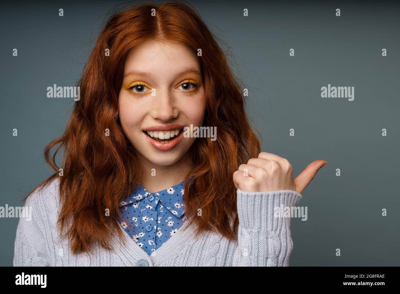 Young ginger happy woman smiling and pointing finger aside isolated ...