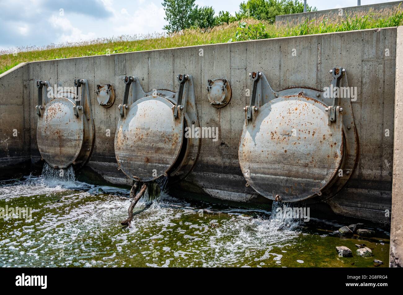 Heavy metal flood control gate discharging into a waterbody Stock Photo ...
