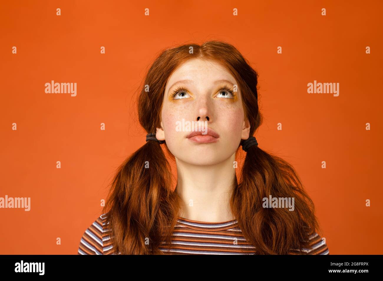 Ginger young woman with tails posing and looking upward isolated over ...