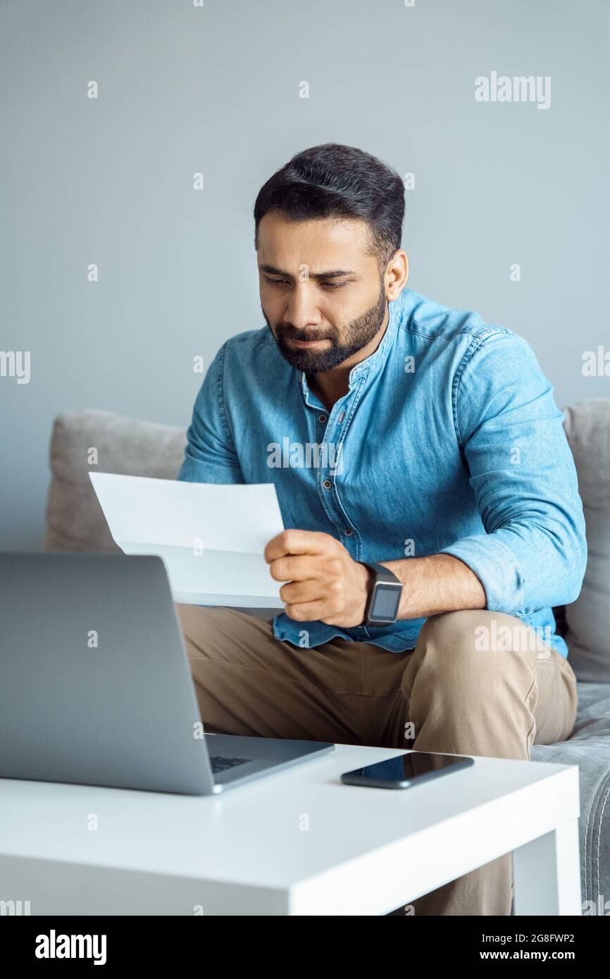 Portrait of concentrated indian businessman with laptop reading ... Portrait of concentrated indian businessman with laptop reading ...