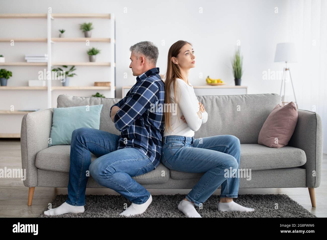 Middle Aged Married Couple Sitting Back To Back On Couch Not Talking