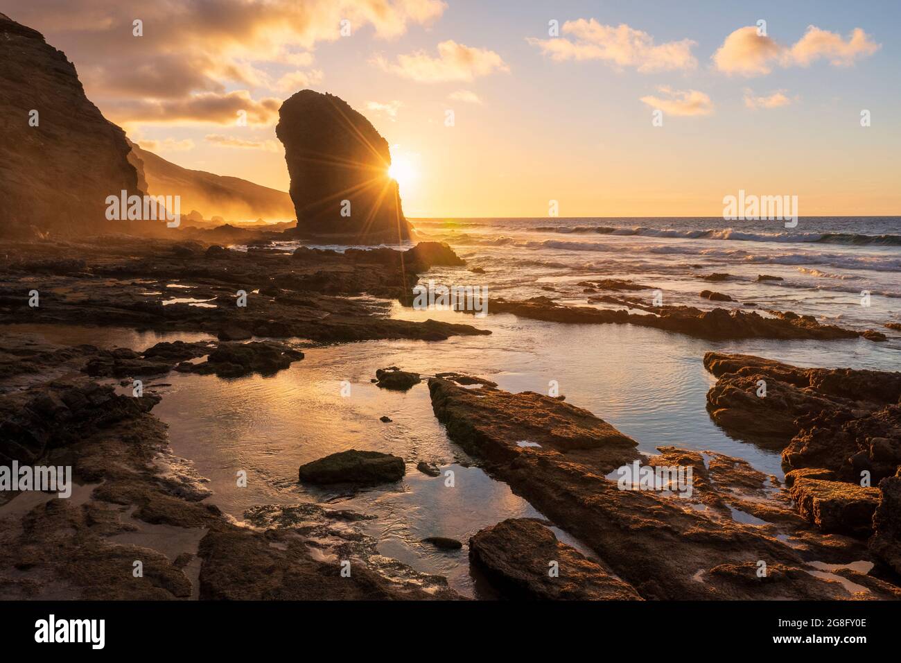 Golden sunset over the giant monolith of Roque Del Moro, Cofete beach ...