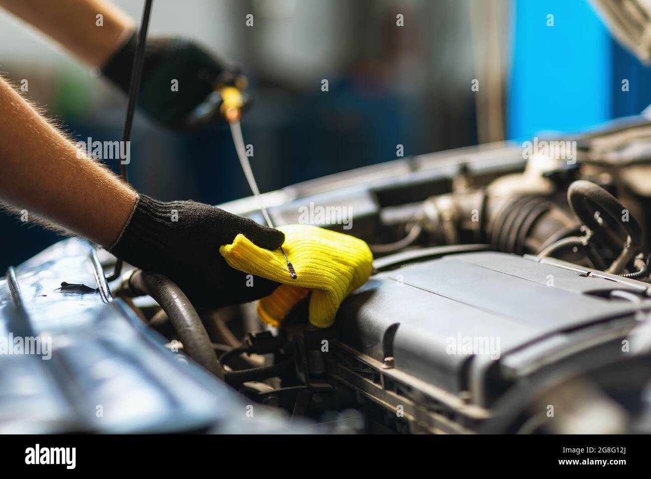 An auto mechanic checks the oil level in a car engine with a special dipstick Stock Photo - Alamy