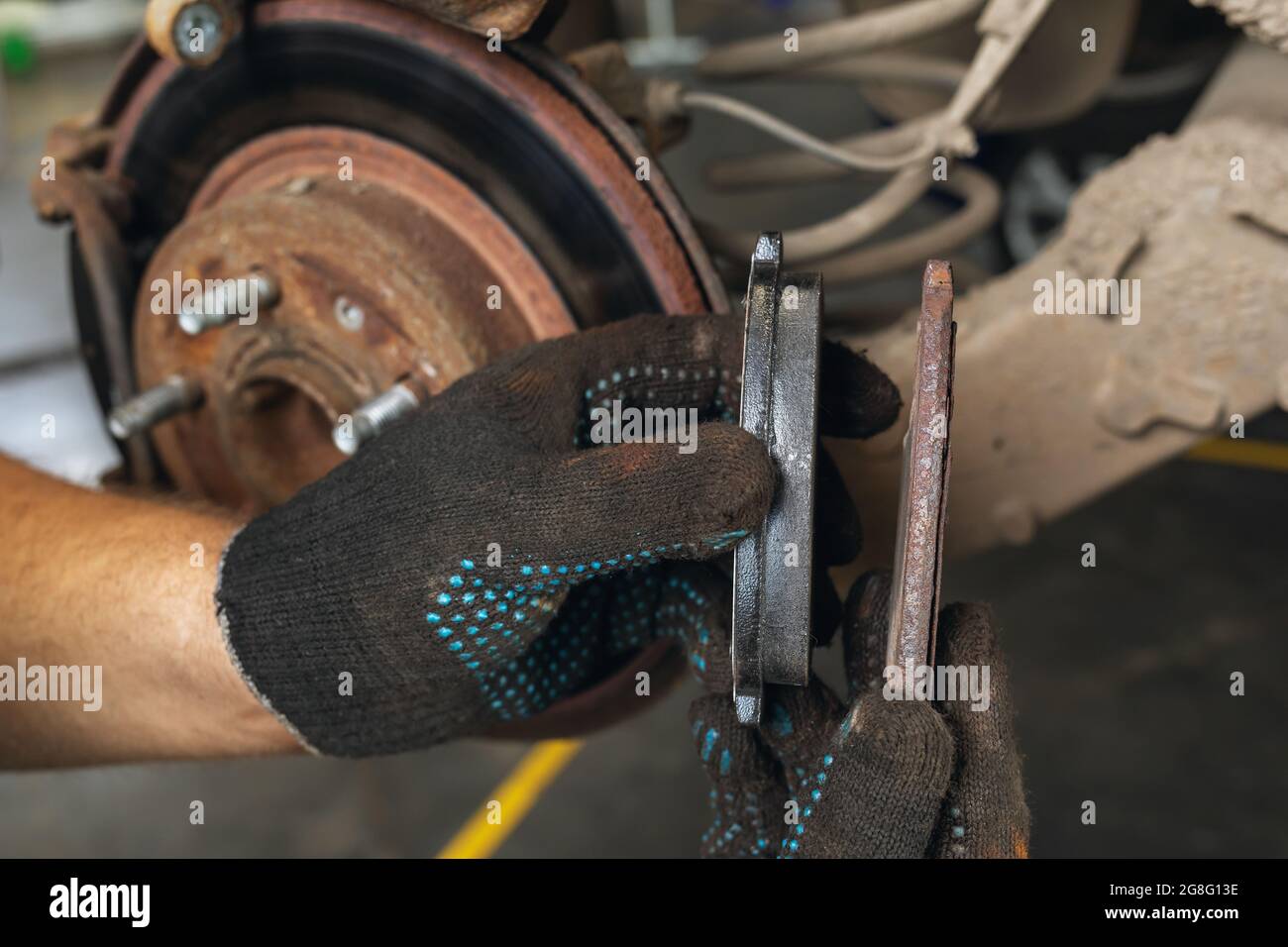 An auto mechanic shows the degree of wear of an old brake pad compared ...