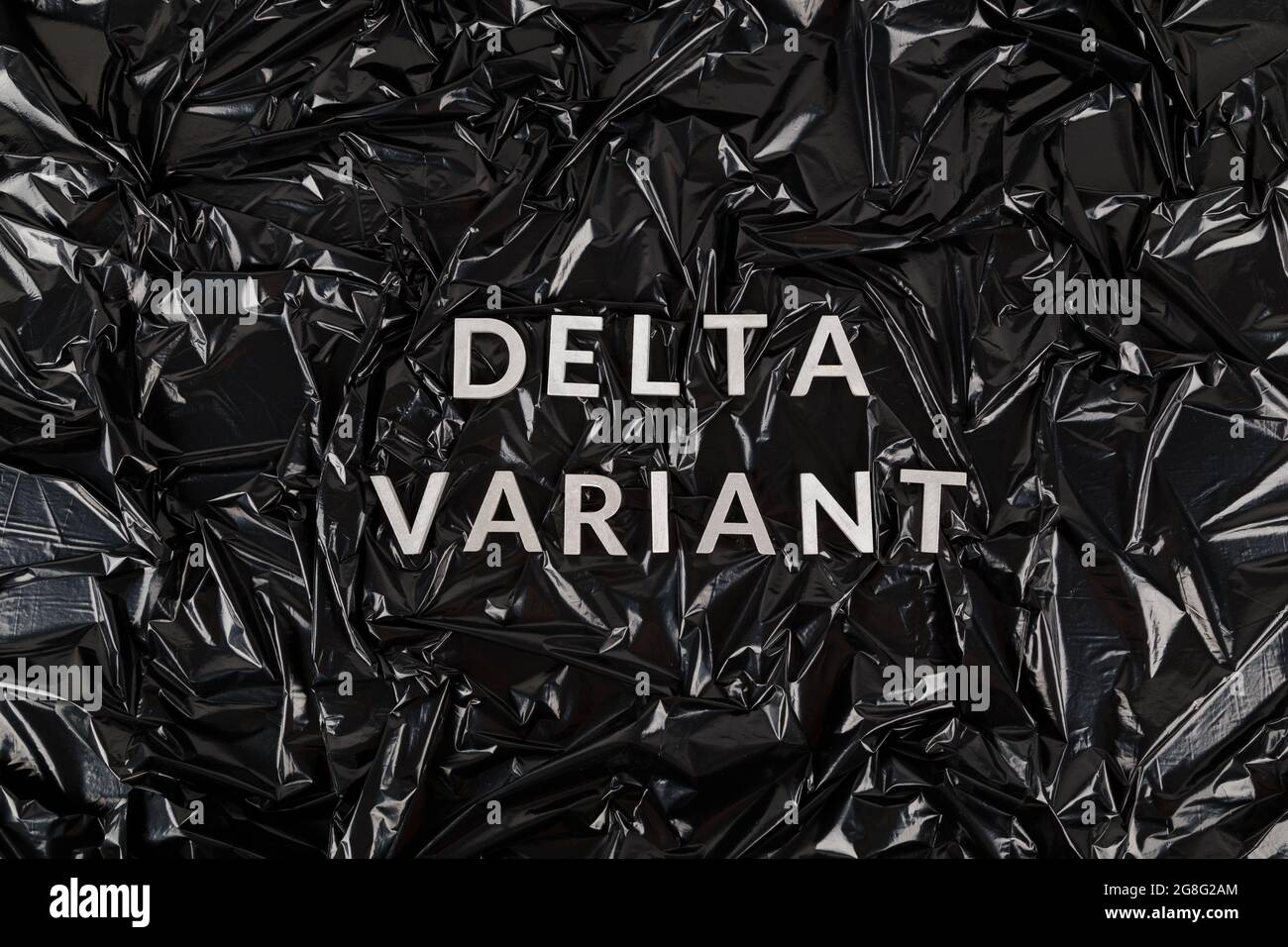 words delta variant laid with silver metal letters on crumpled black ...