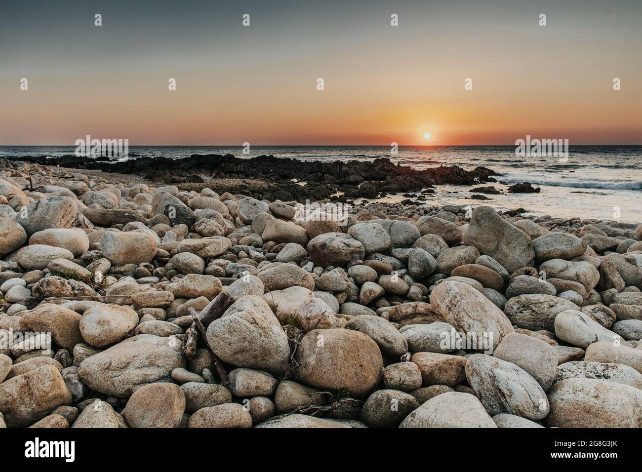 Mesmerizing sunset above the sea seen through coastal rock Stock Photo ...