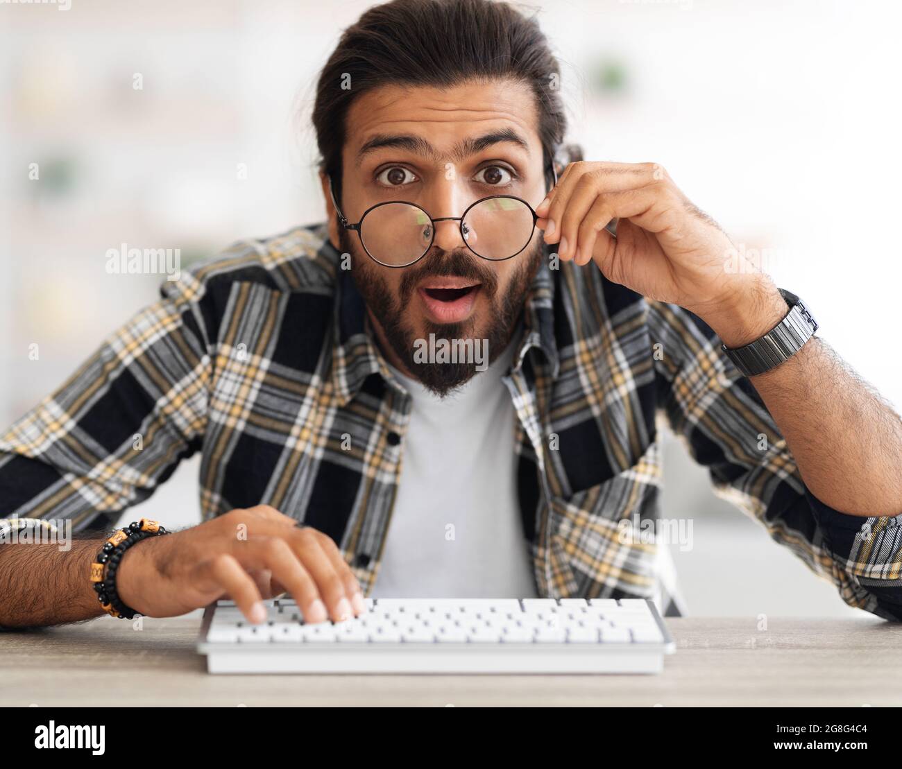 Excited arab guy freelancer looking at camera, using pc keyboard Stock ...