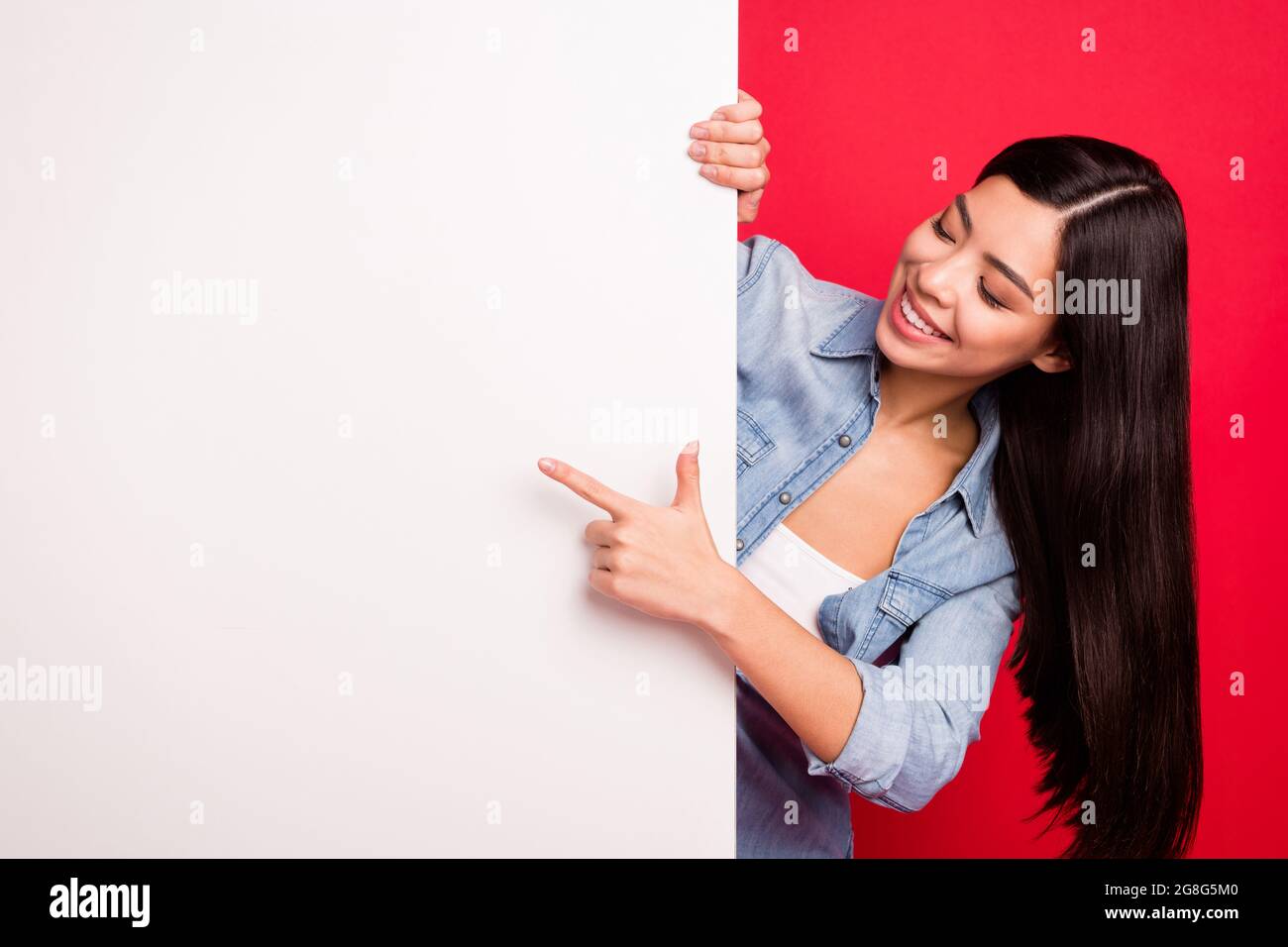 Portrait of attractive cheerful girl demonstrating big blank poster ad ...