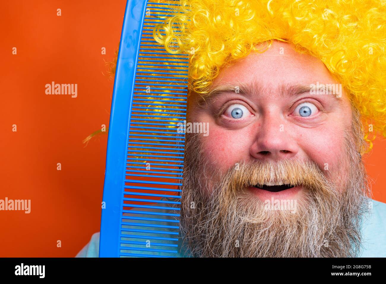 Fat amazed man with beard, tattoos and sunglasses combs himself with a ...