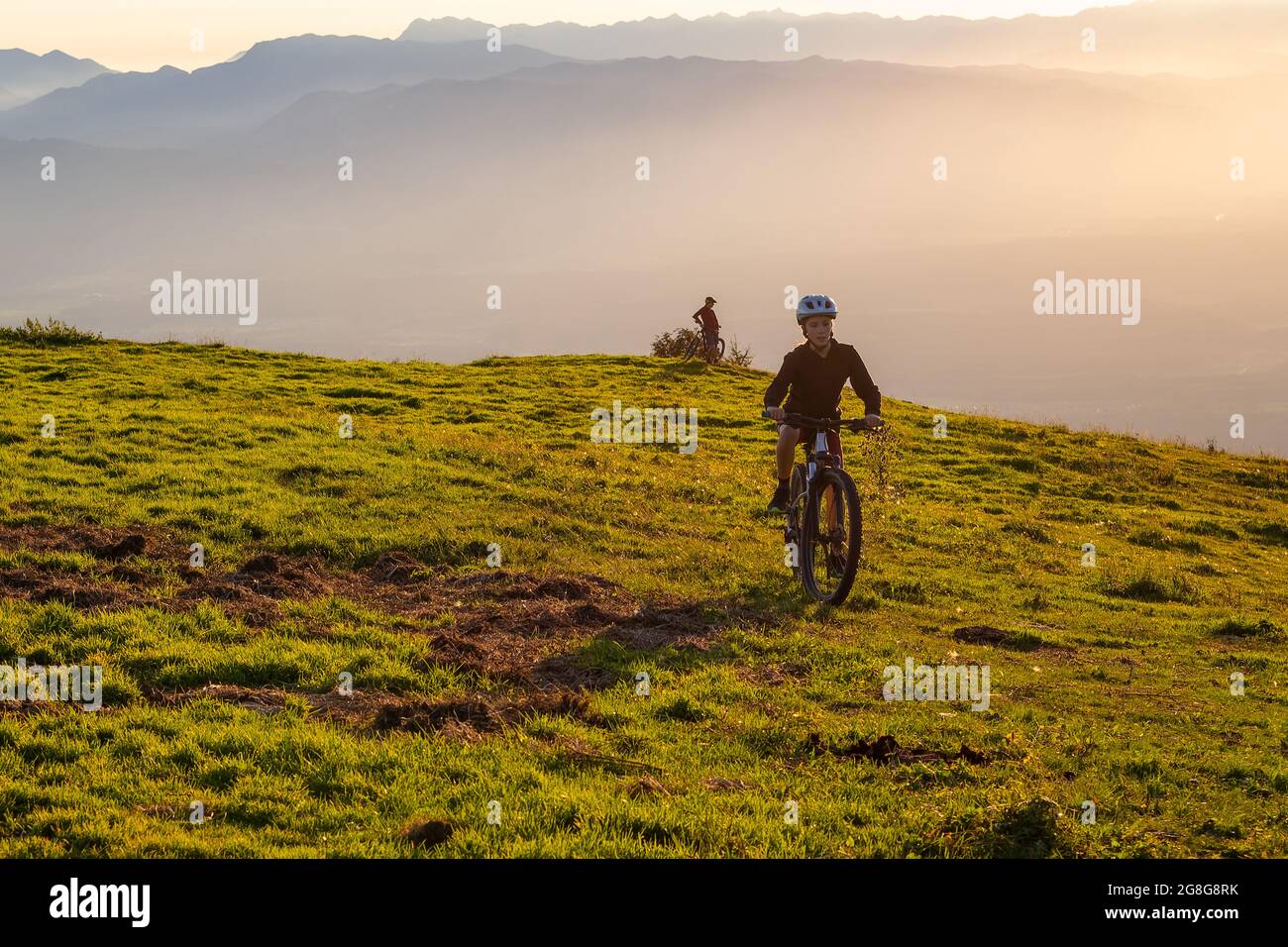 Girl child riding mountain bike into the sunset. Beautiful golden ...