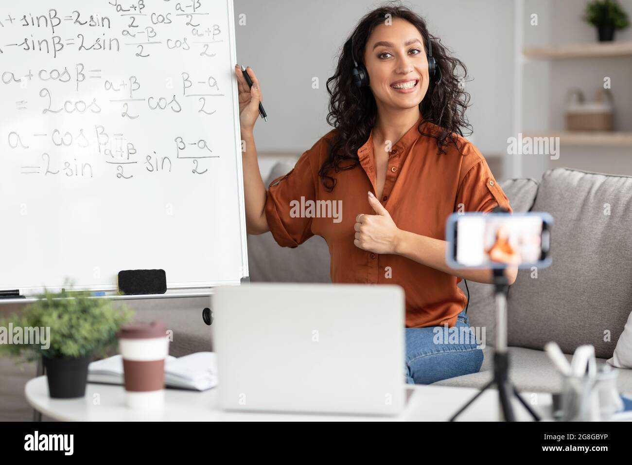 Female teacher showing thumb up gesture, explaining math to students ...