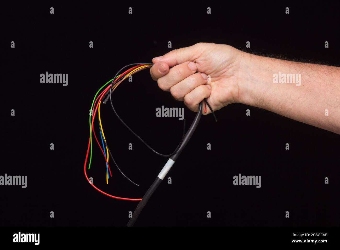 Colored electric cable in hand on black background Stock Photo - Alamy