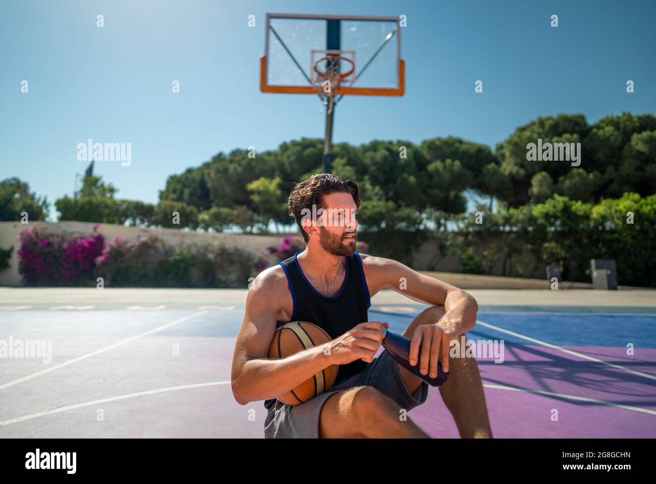 tired basketball player after the match, sits on the basketball field ...