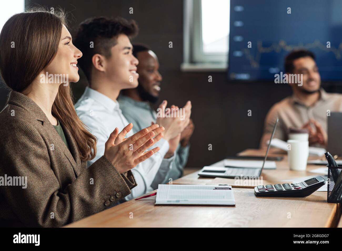 Smiling happy colleagues having training in boardroom, clapping hands ...