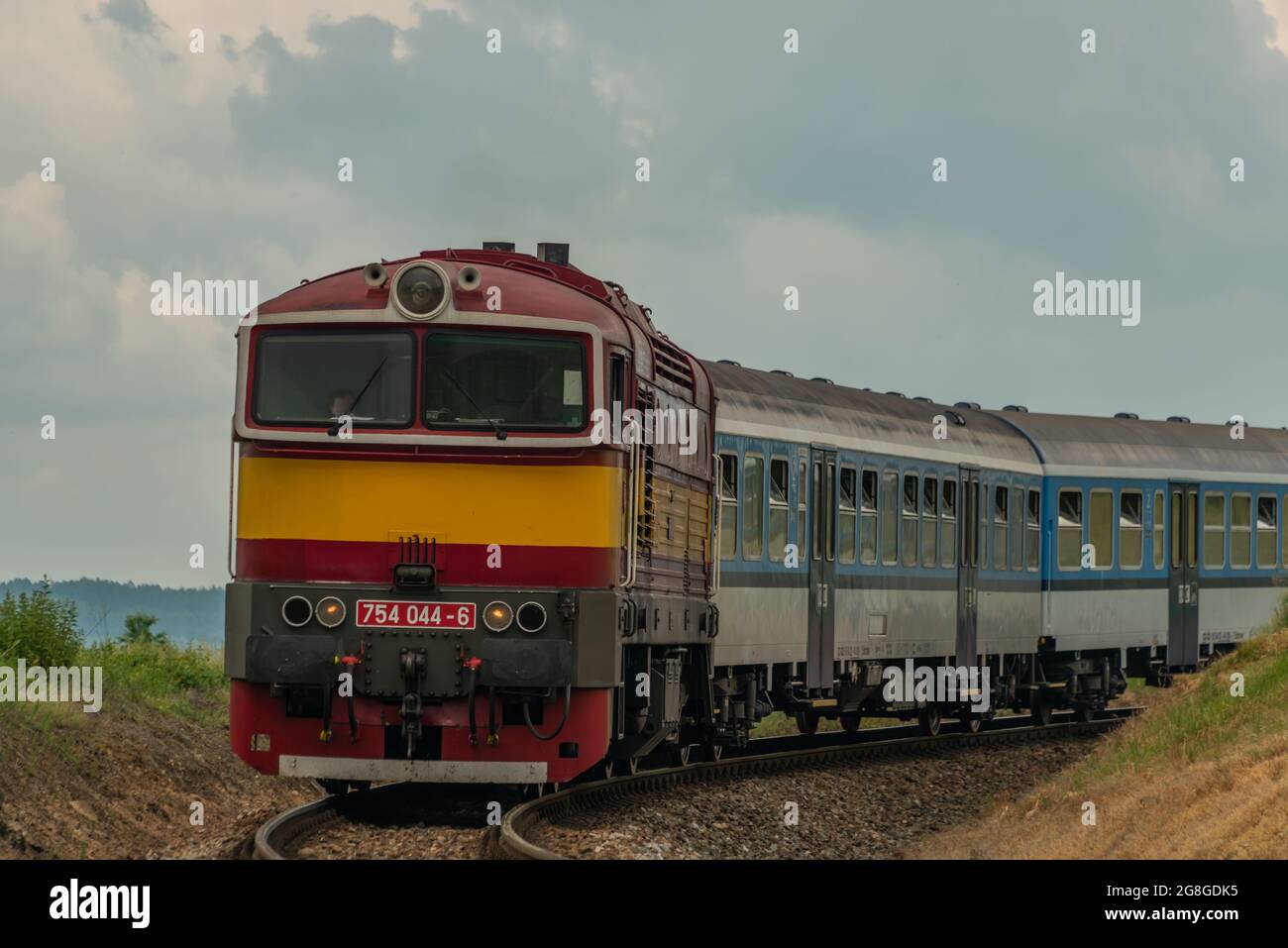 Diesel red train near Sazava river in south of Prague in summer cloudy ...
