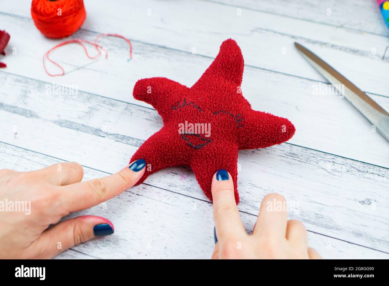 Female hands holding a handmade red star-shaped toy Stock Photo - Alamy