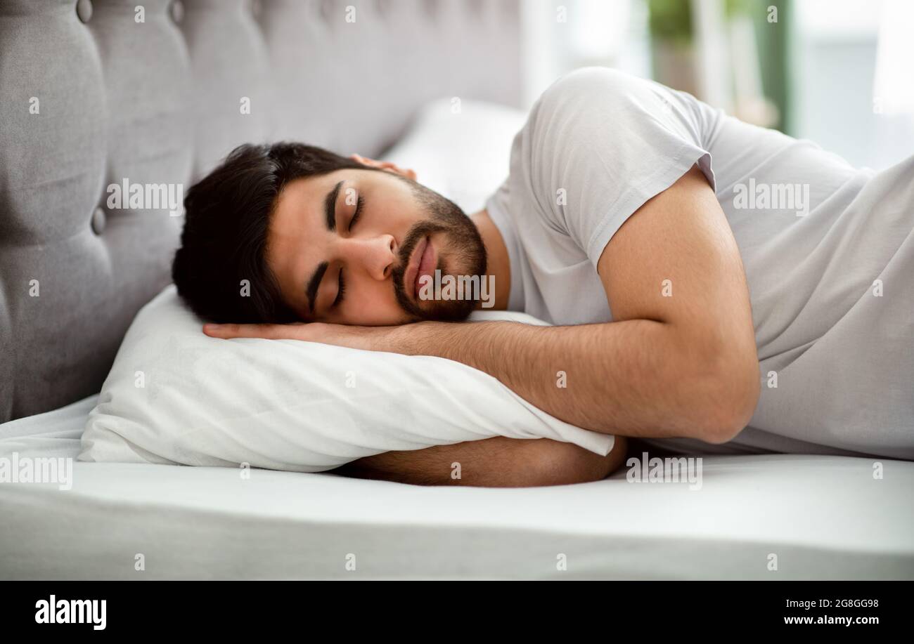 Comfortable sleep. Millennial arab man sleeping peacefully and see sweet dreams, lying in comfy ...