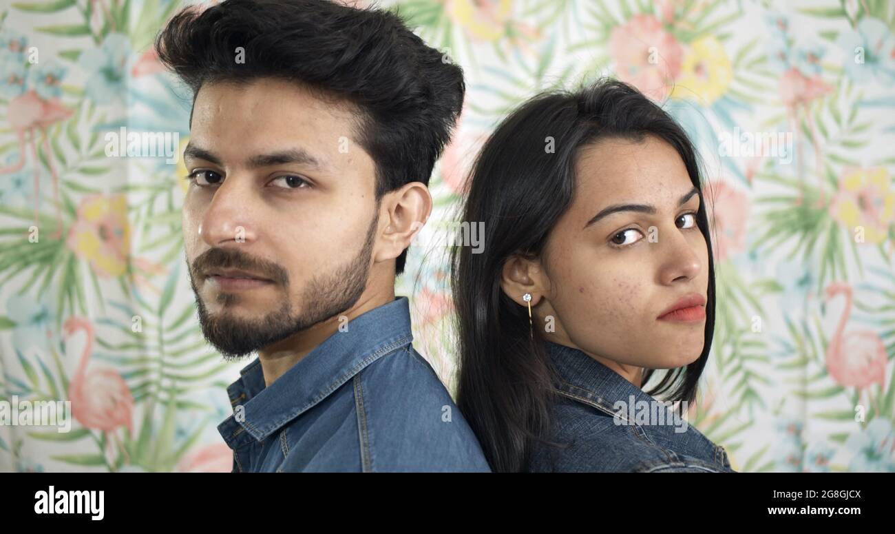 Young Indian couple standing back to back with serious face expression ...