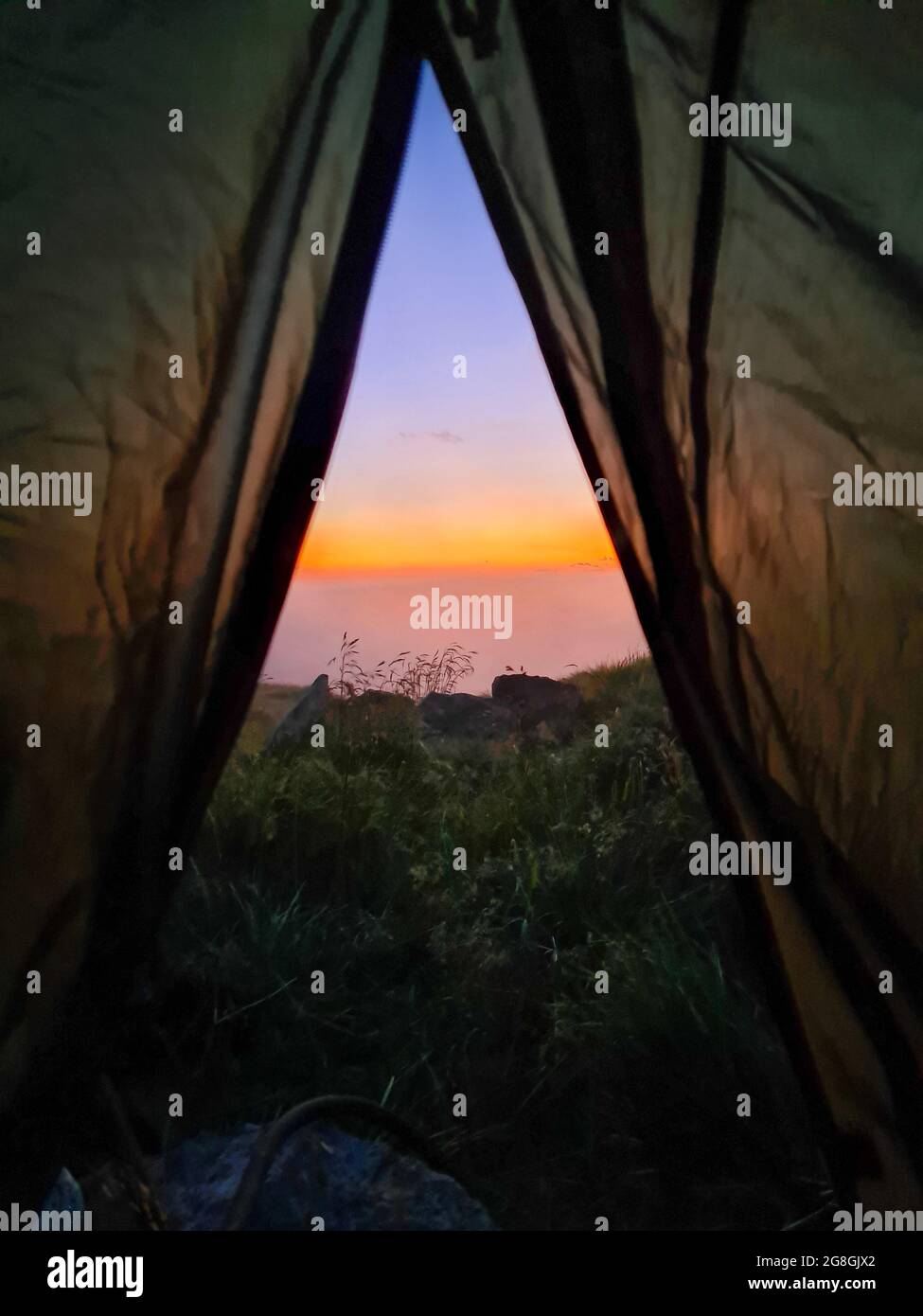 view of sunset above the mountains from camping tent. hiking concept ...