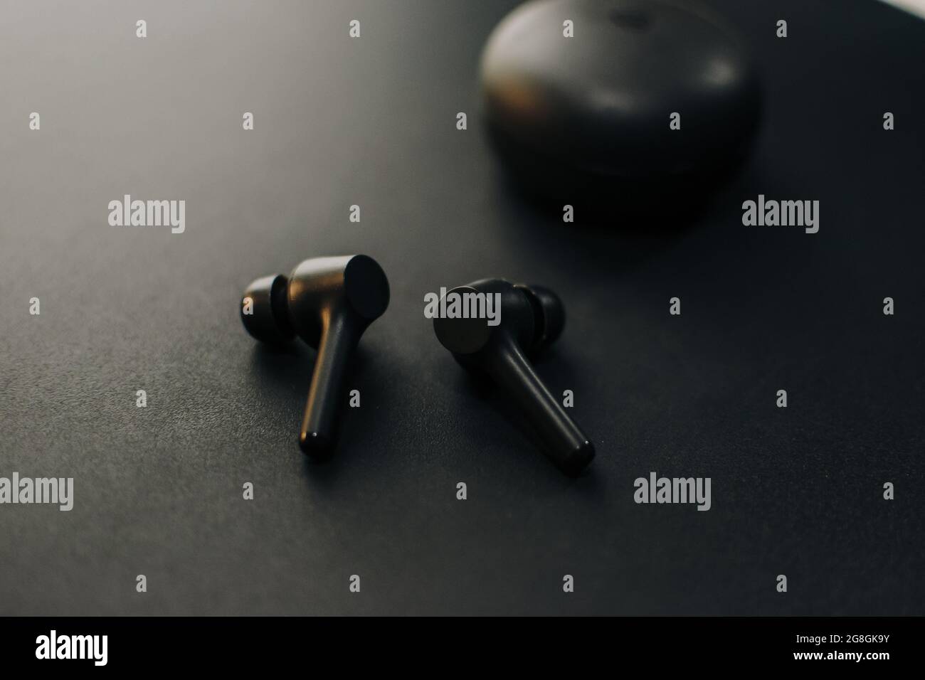 Top view closeup of a pair of wireless earphones placed on a black ...