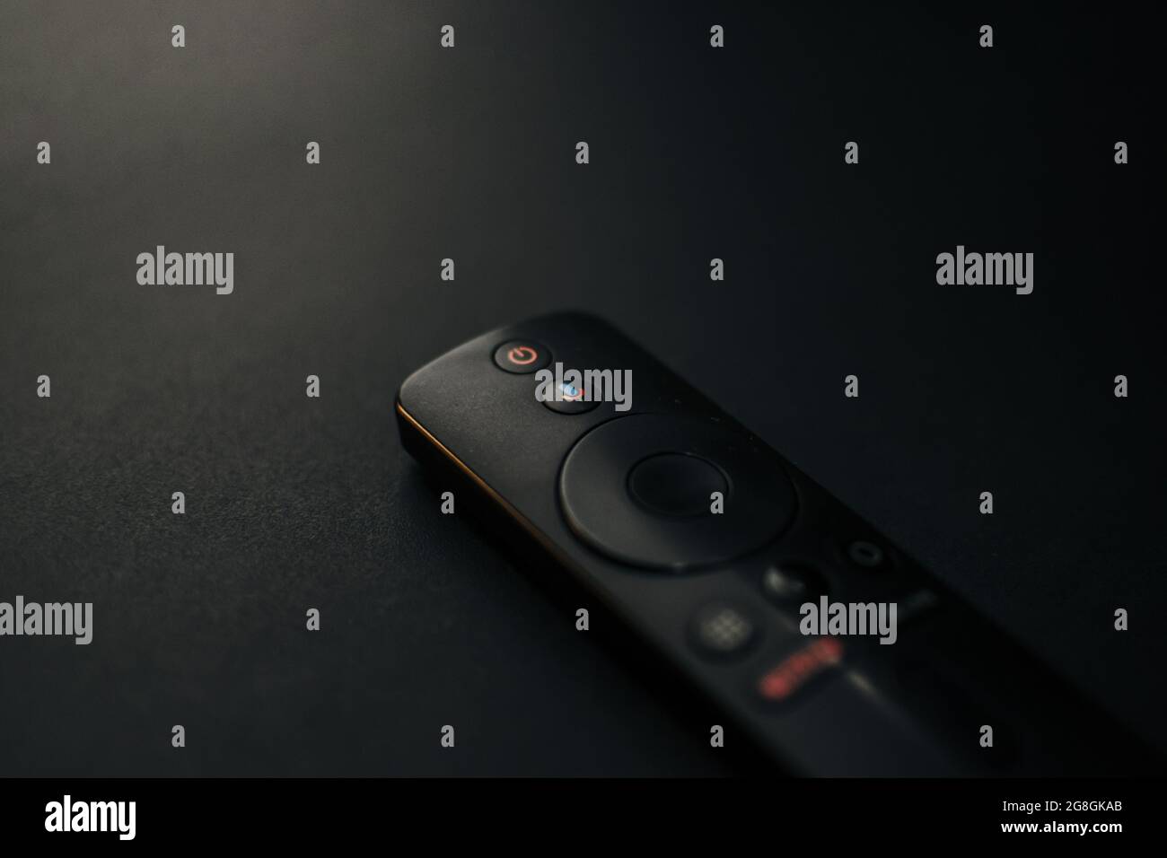 Top view closeup of a black remote placed on a plain black background ...