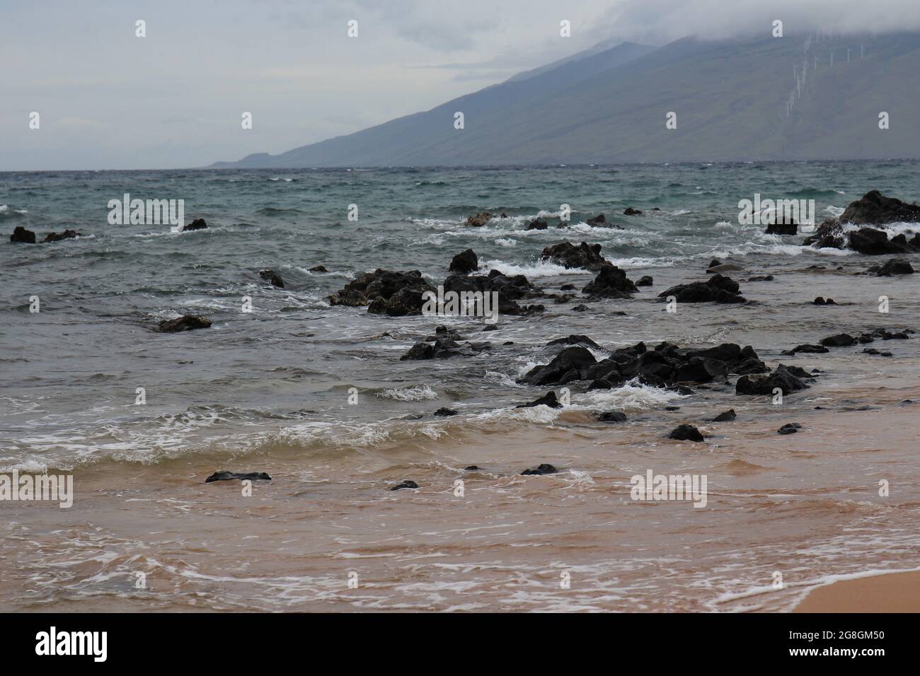 A beach landscape with sand, volcanic rocks, the Pacific Ocean and a ...