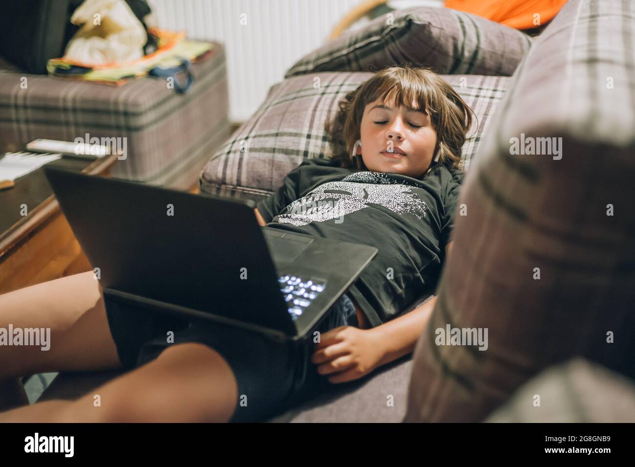 Young teenage boy sleeping in front of a laptop computer. Home ...