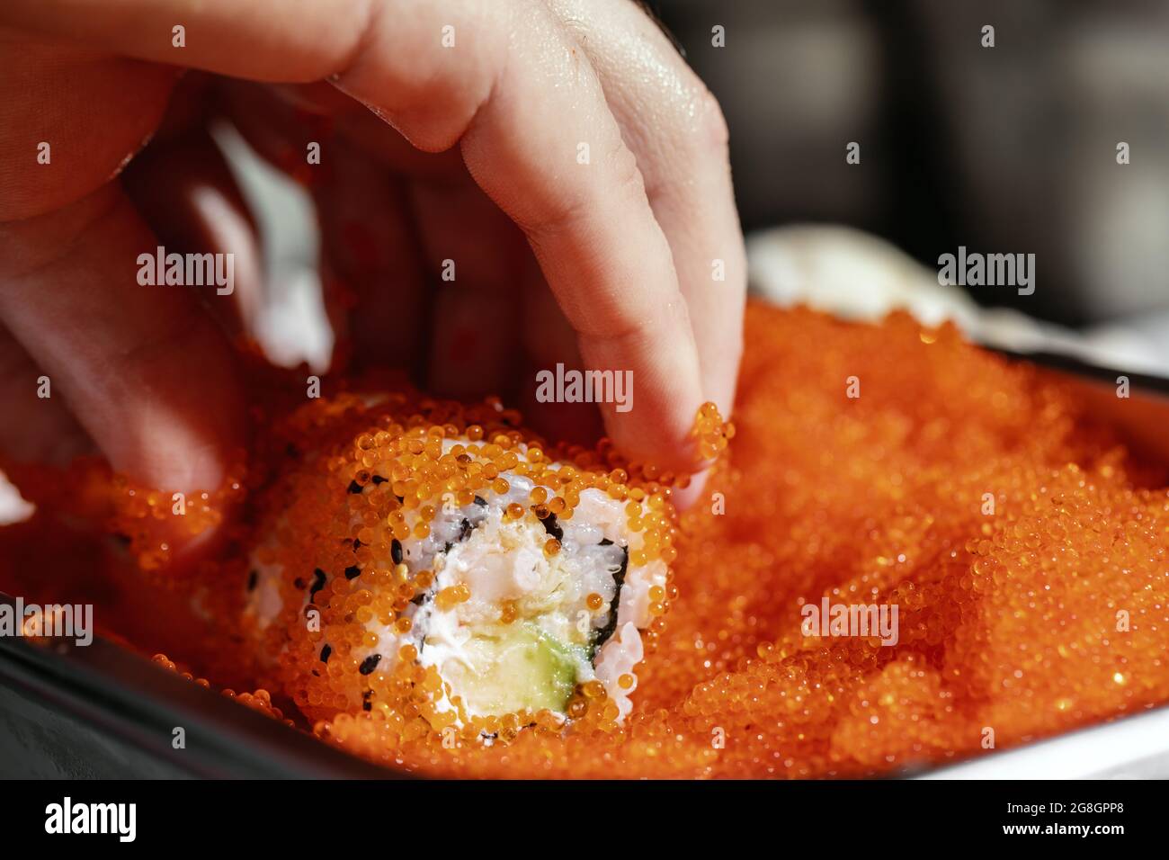 Closeup of chef hands rolling up sushi in flying fish roe (Tobiko) red ...