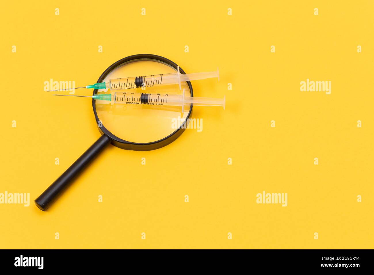 A Magnifier with Medical Syringe Lying on Yellow Table - Vaccination ...