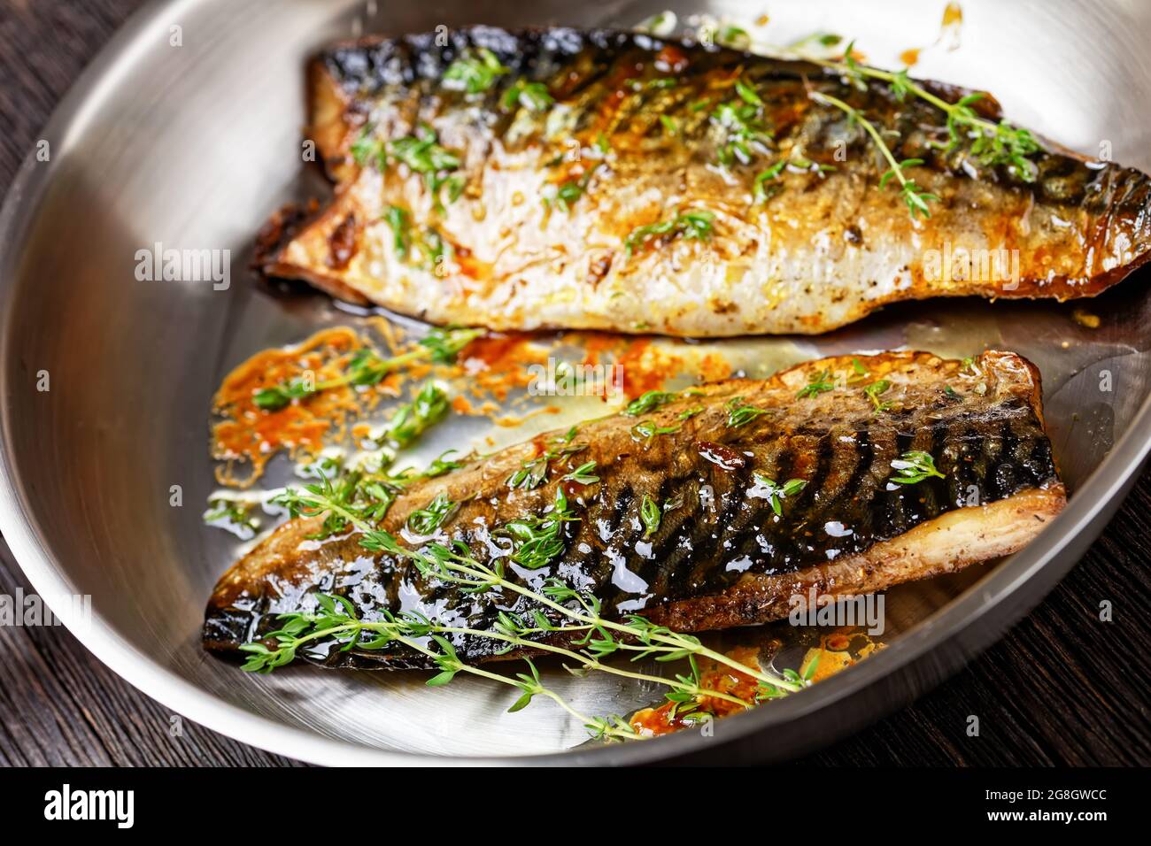 close-up of fried mackerel fillets with spices and thyme in a pan on a ...