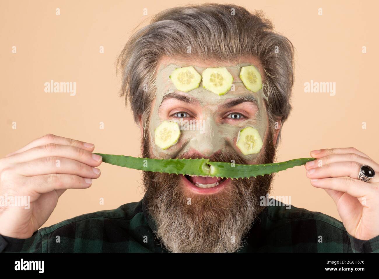 Funny male model with clay mask and cucumber slices, aloe vera ...