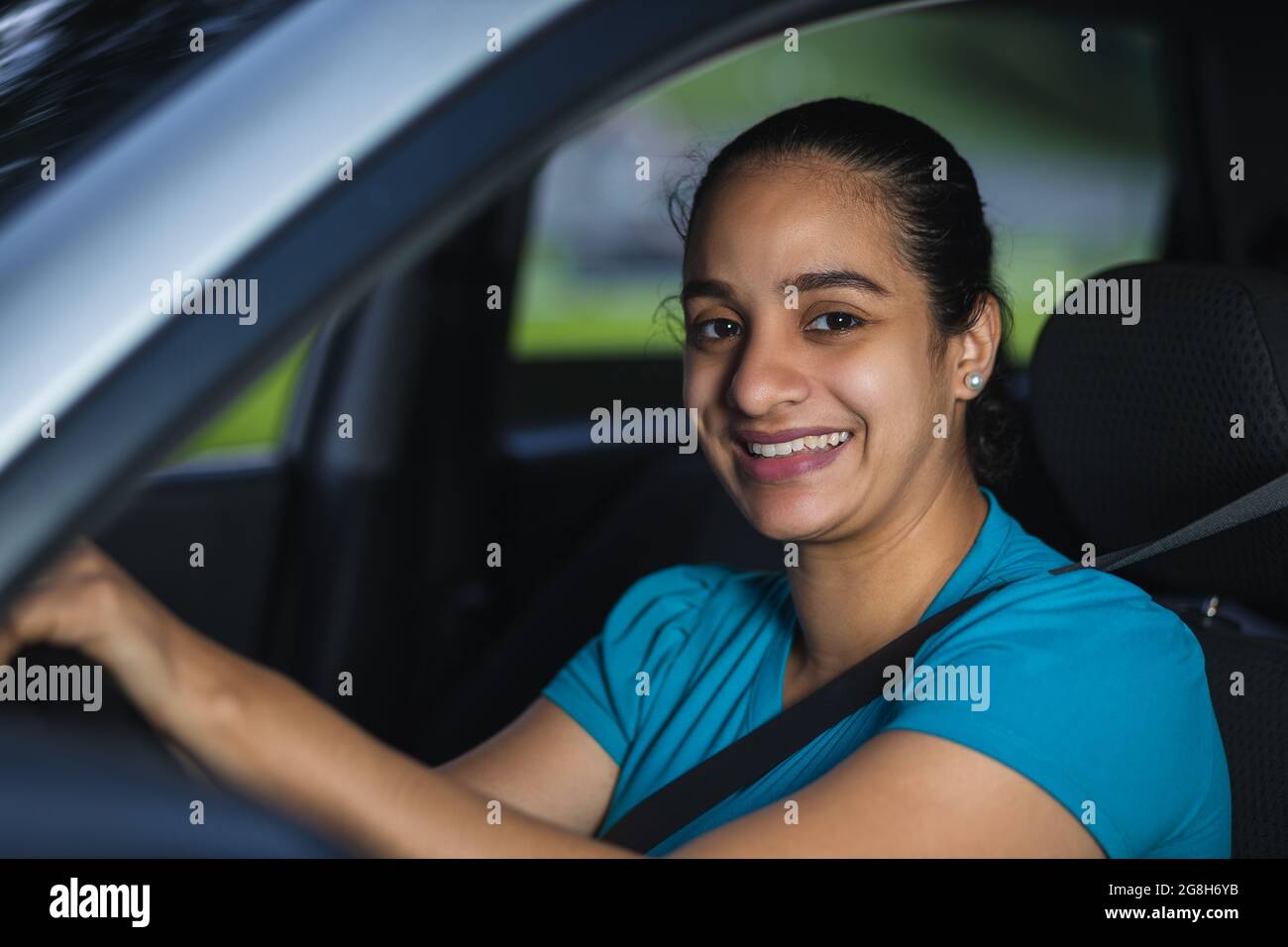 Young cheerful Hispanic female driving her car Stock Photo - Alamy
