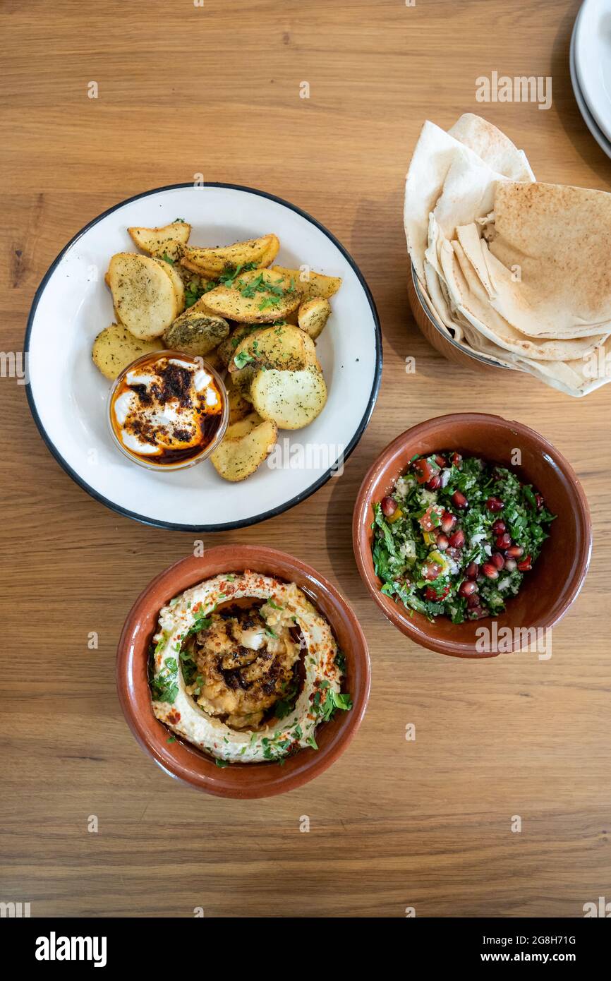 Top down view of a mezze table with za'atar fries, hummus, tabbouleh ...
