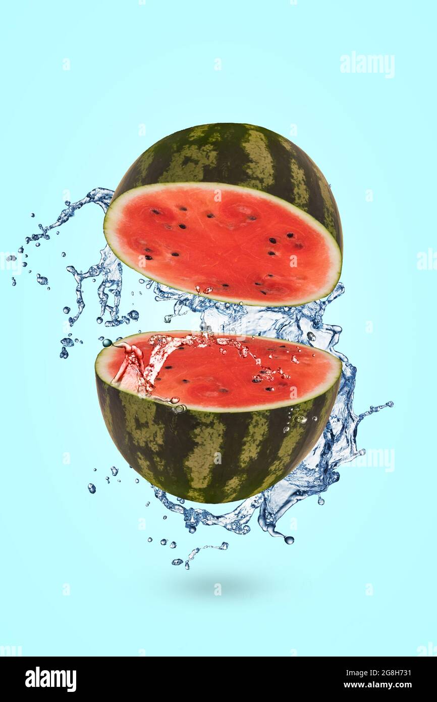 Ripe watermelon cut in half flying in the air, with splash of water ...