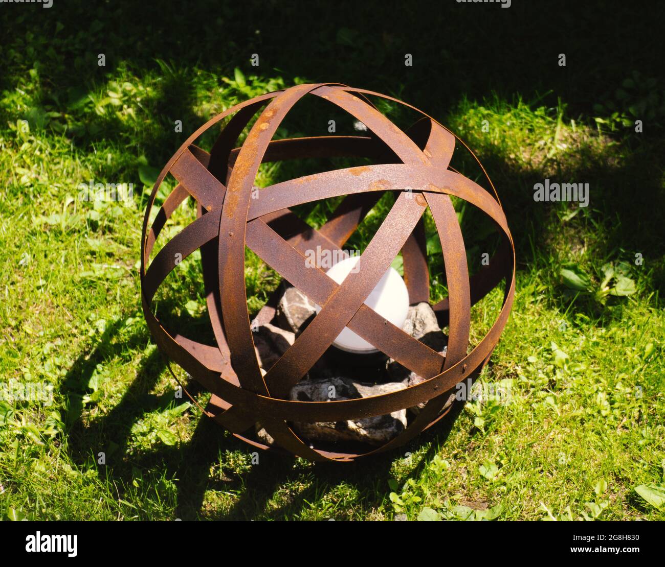 Spherical garden decor made of rusty metal on the grass Stock Photo - Alamy