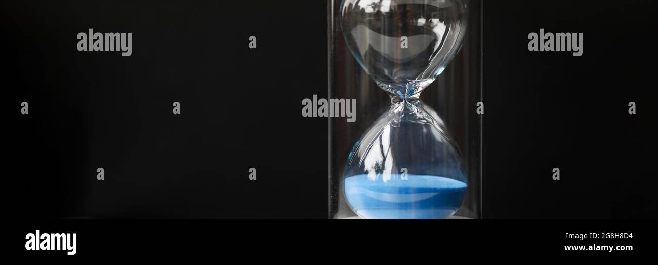 Stylish glass hourglass with blue sand close up Stock Photo - Alamy