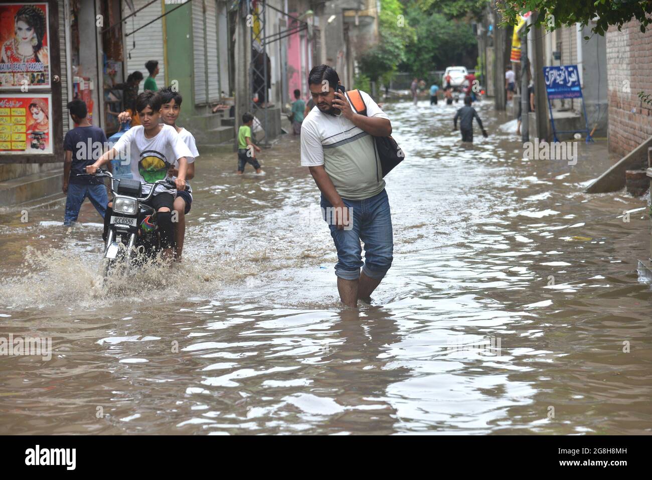 Lahore, Pakistan. 20th July, 2021. Pakistani commuters wade through a ...