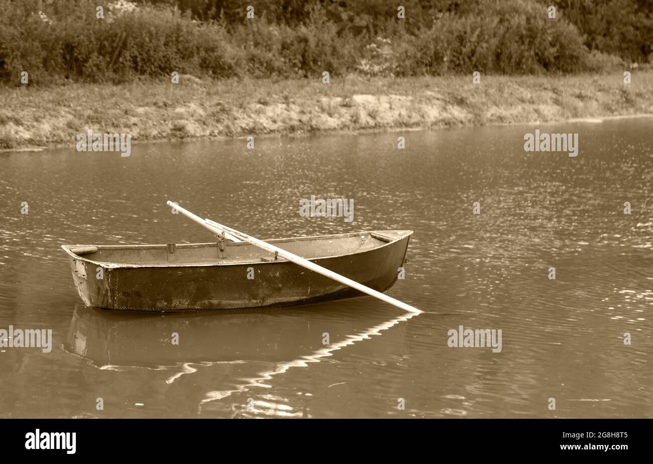 Empty fishing boat with oars in the middle of the lake, black and white ...