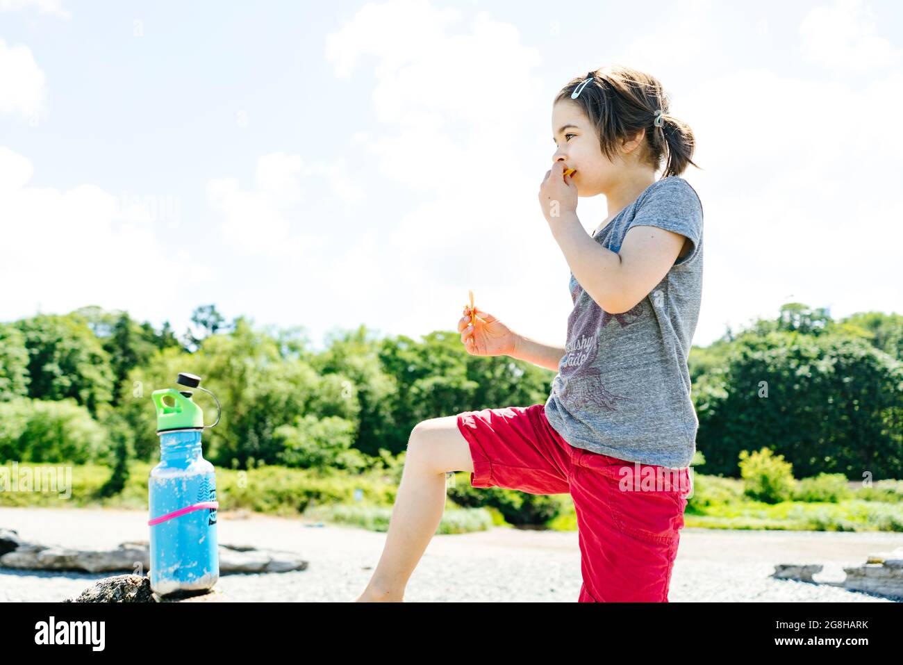 Side view of a child eating a snack on the beach Stock Photo - Alamy