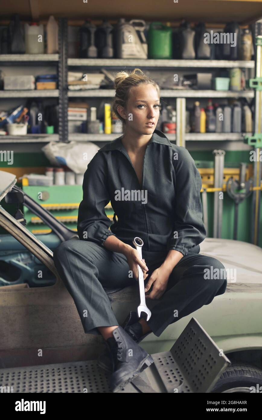 Female mechanician sitting on the car in the garage Stock Photo - Alamy